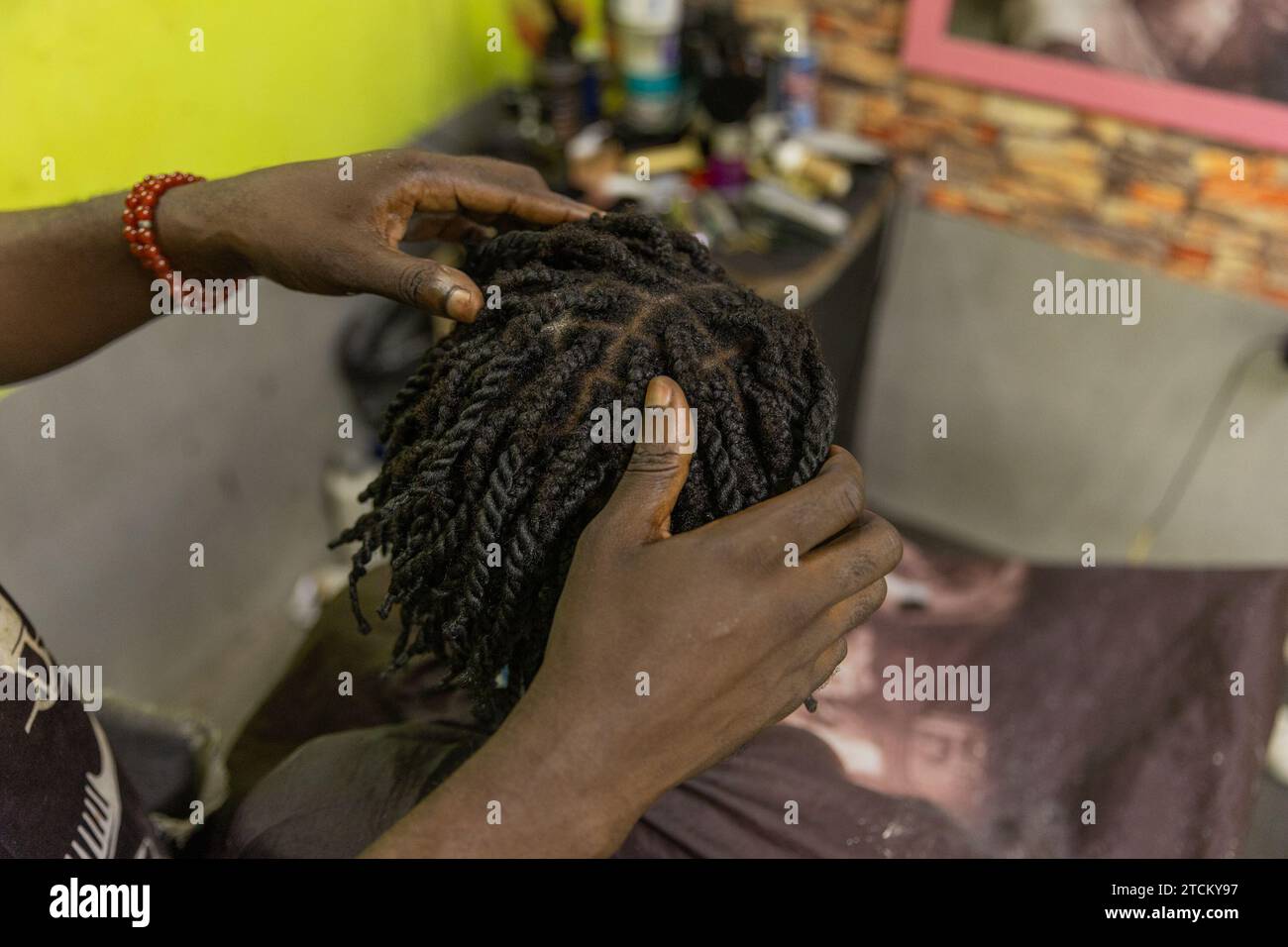 A barber fixes his client's braids in a salon in Africa Stock Photo - Alamy