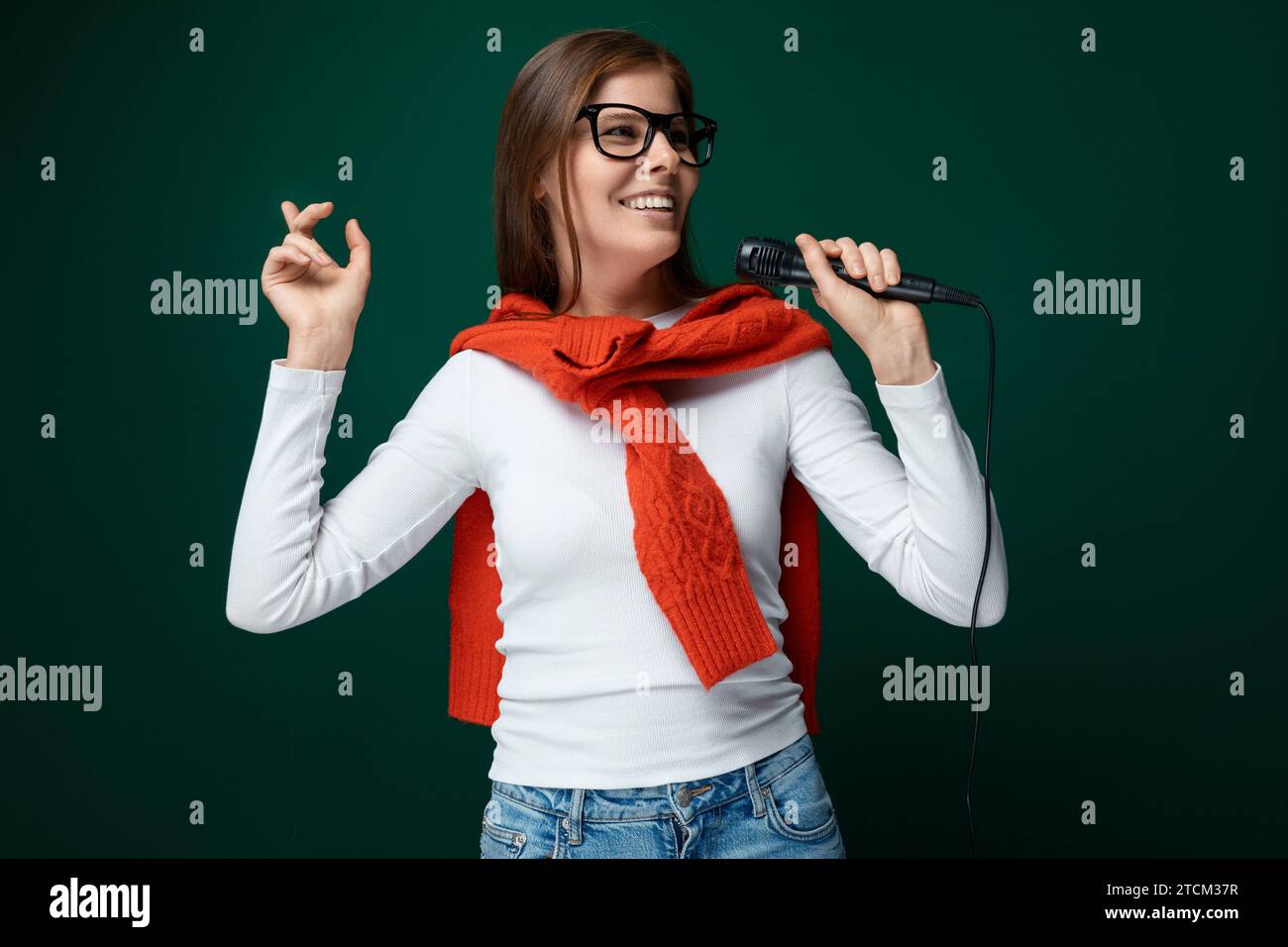 Charming young woman with a microphone sings a karaoke song Stock Photo ...