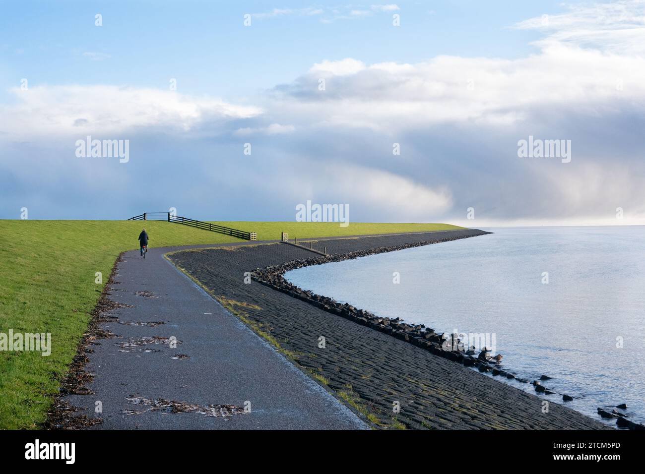 Long, straight dike, grass, basalt blocks and a cycle path, in the ...