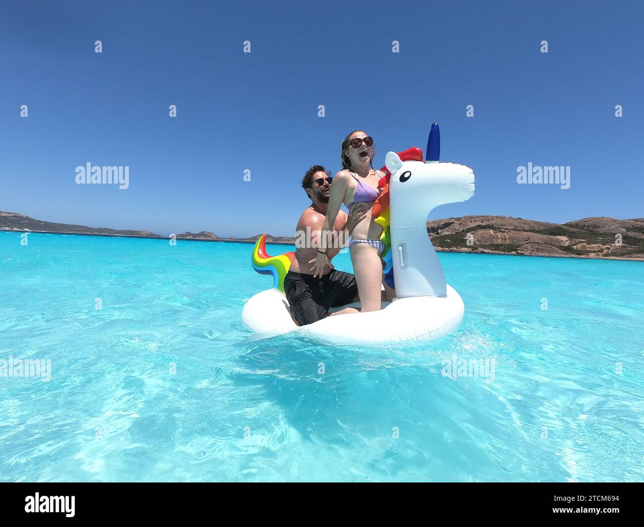 A Smiling Man And Woman Enjoying A Sunny Day On An Inflatable Swan