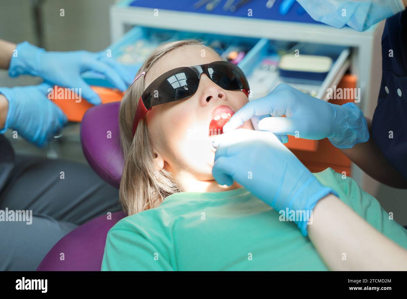 Little scared girl sitting in chair in dentist doctor office ...
