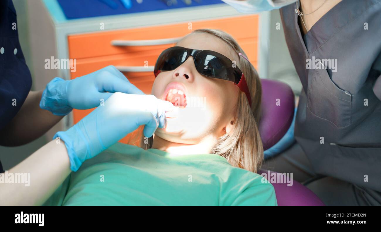 Little scared girl sitting in chair in dentist doctor office ...