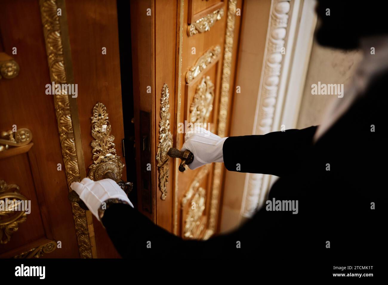Close up of butler opening heavy wooden doors in palace with gloved ...