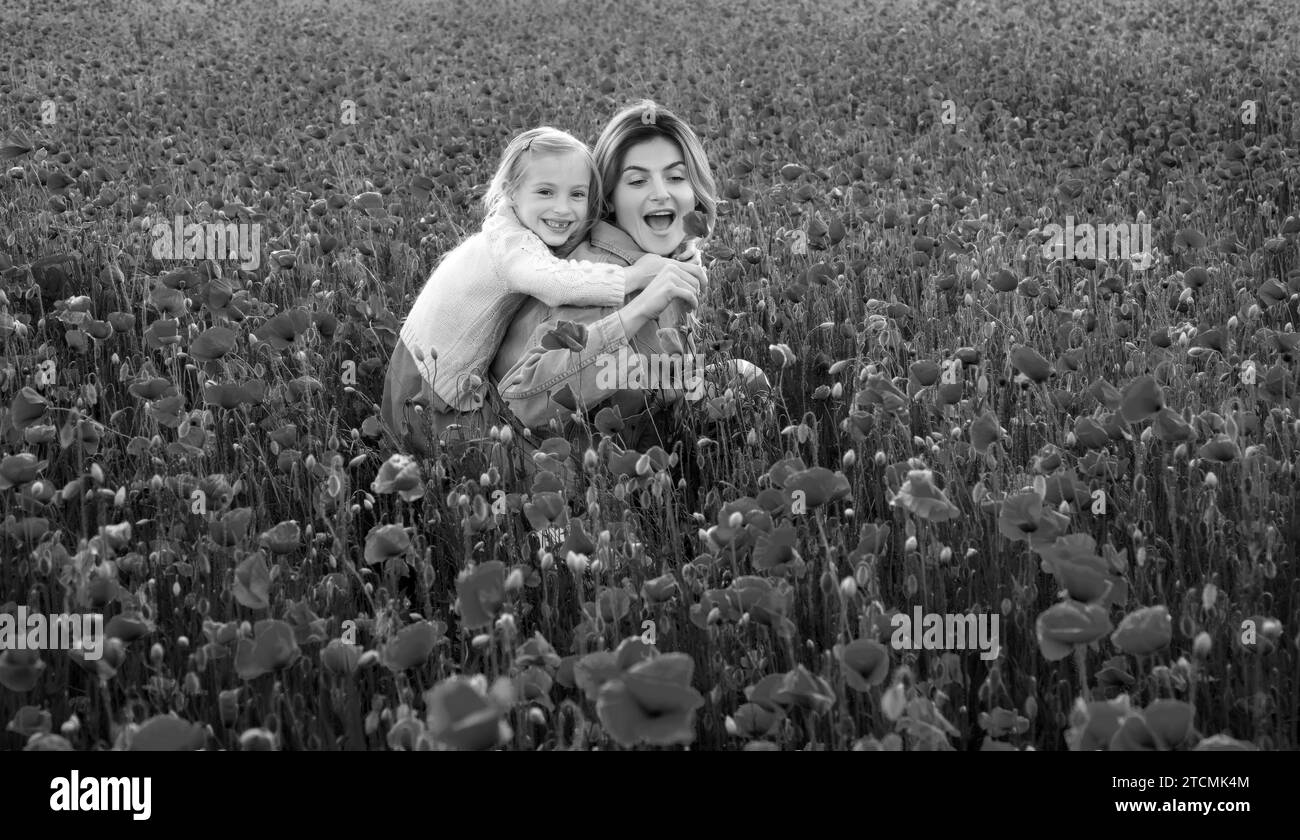 Beautiful mother and daughter in spring poppy flower field. Mom holds ...