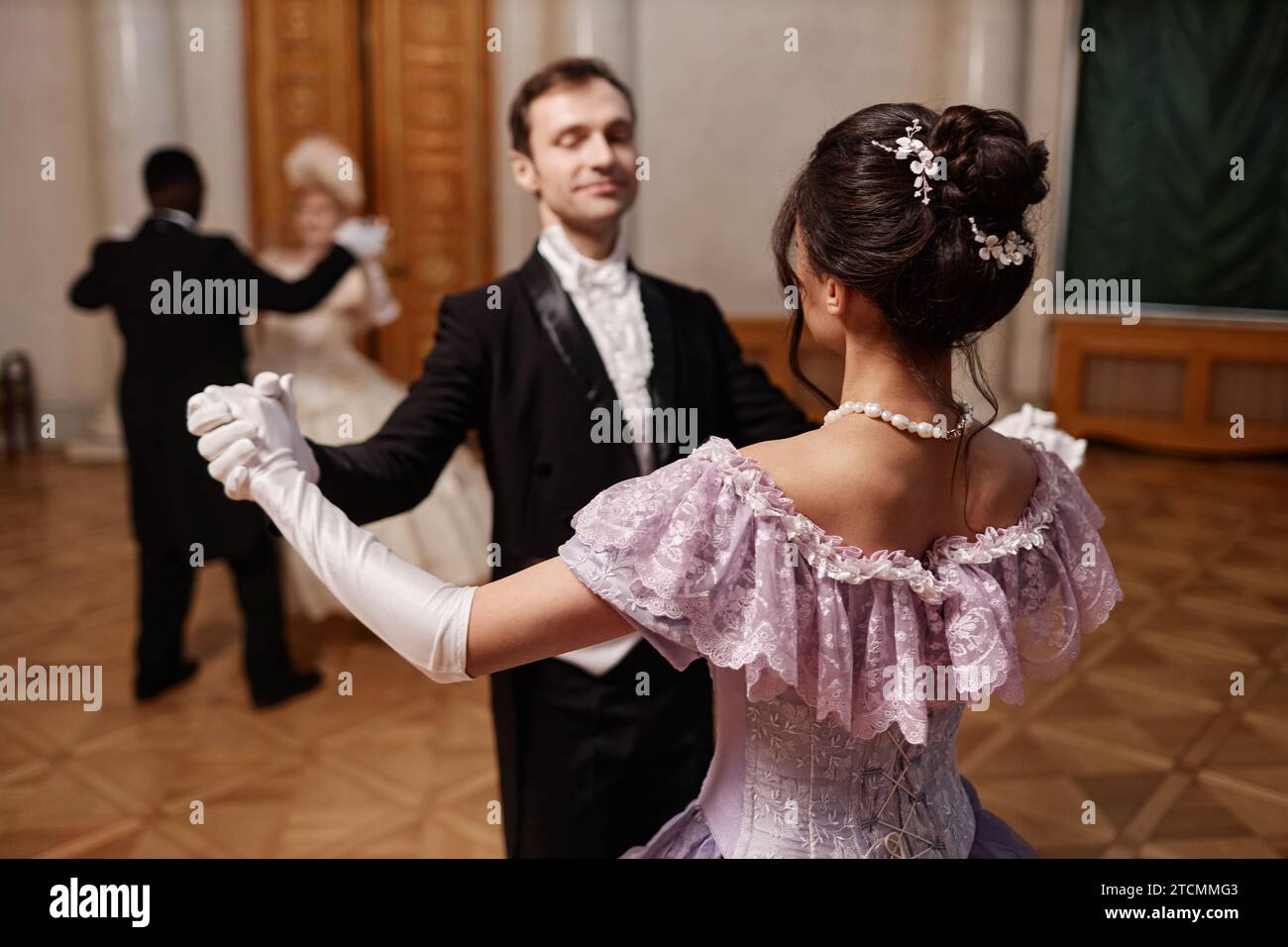 Back view of young lady wearing ballgown dancing waltz with gentleman ...