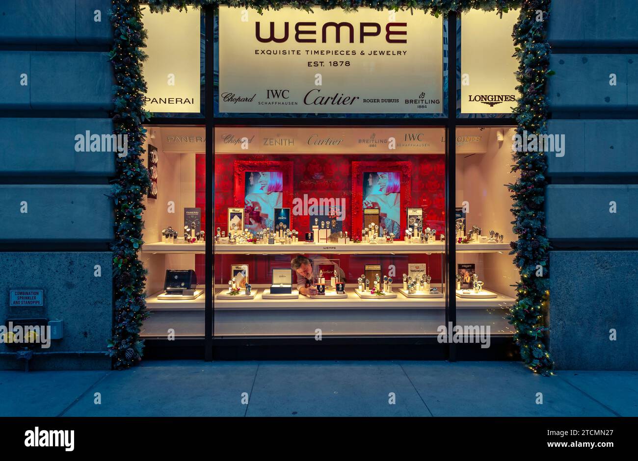 A worker adjusts the watches in the Christmas themed window display of ...