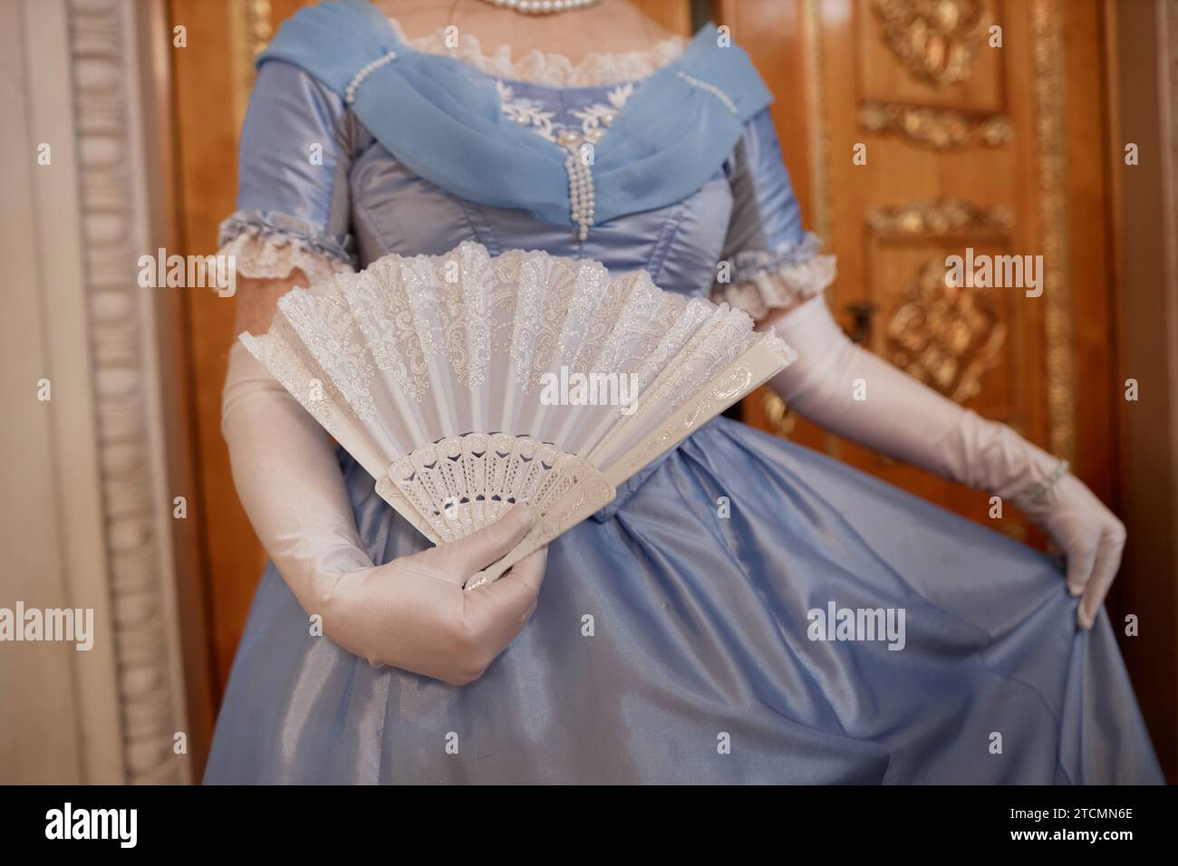 Close up of lady wearing blue ballgown curtsying and holding fal in ...