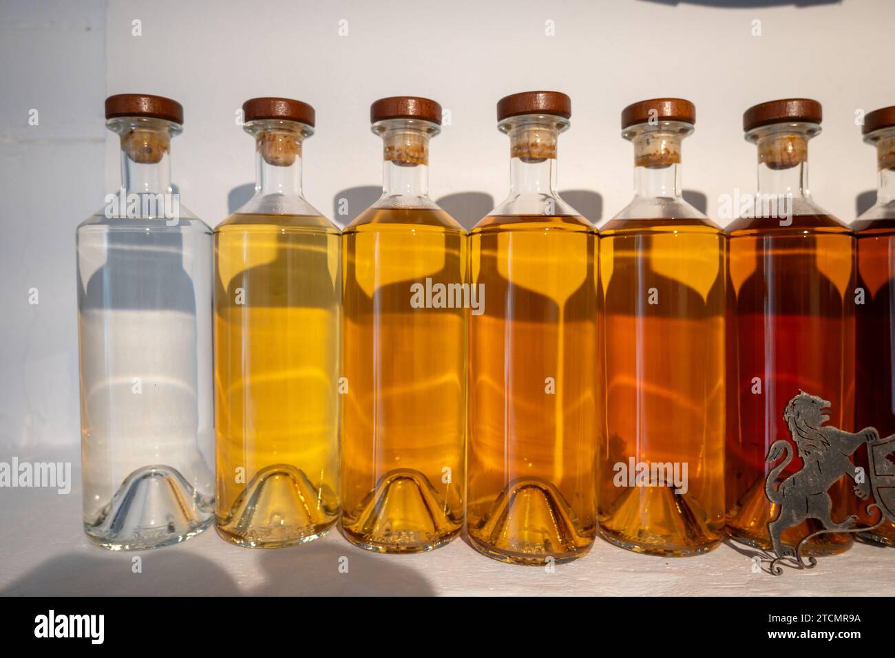 Different colours and ages of cognac spirits in bottles in distillery ...