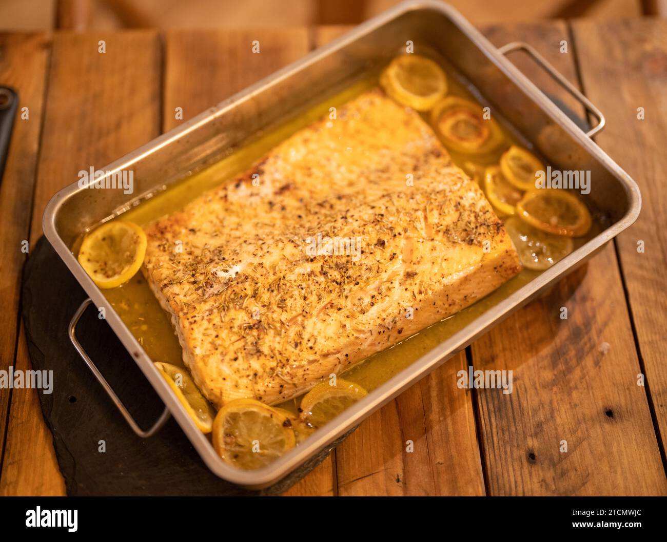 A stainless steel tray with a lightly seasoned fish fillet, garnished ...