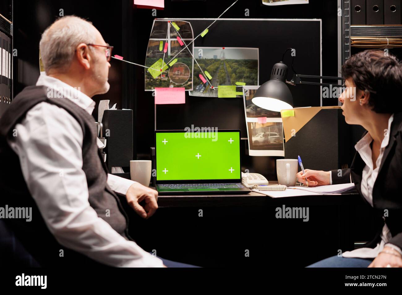 Police officers looking at laptop computer with greenscreen display ...