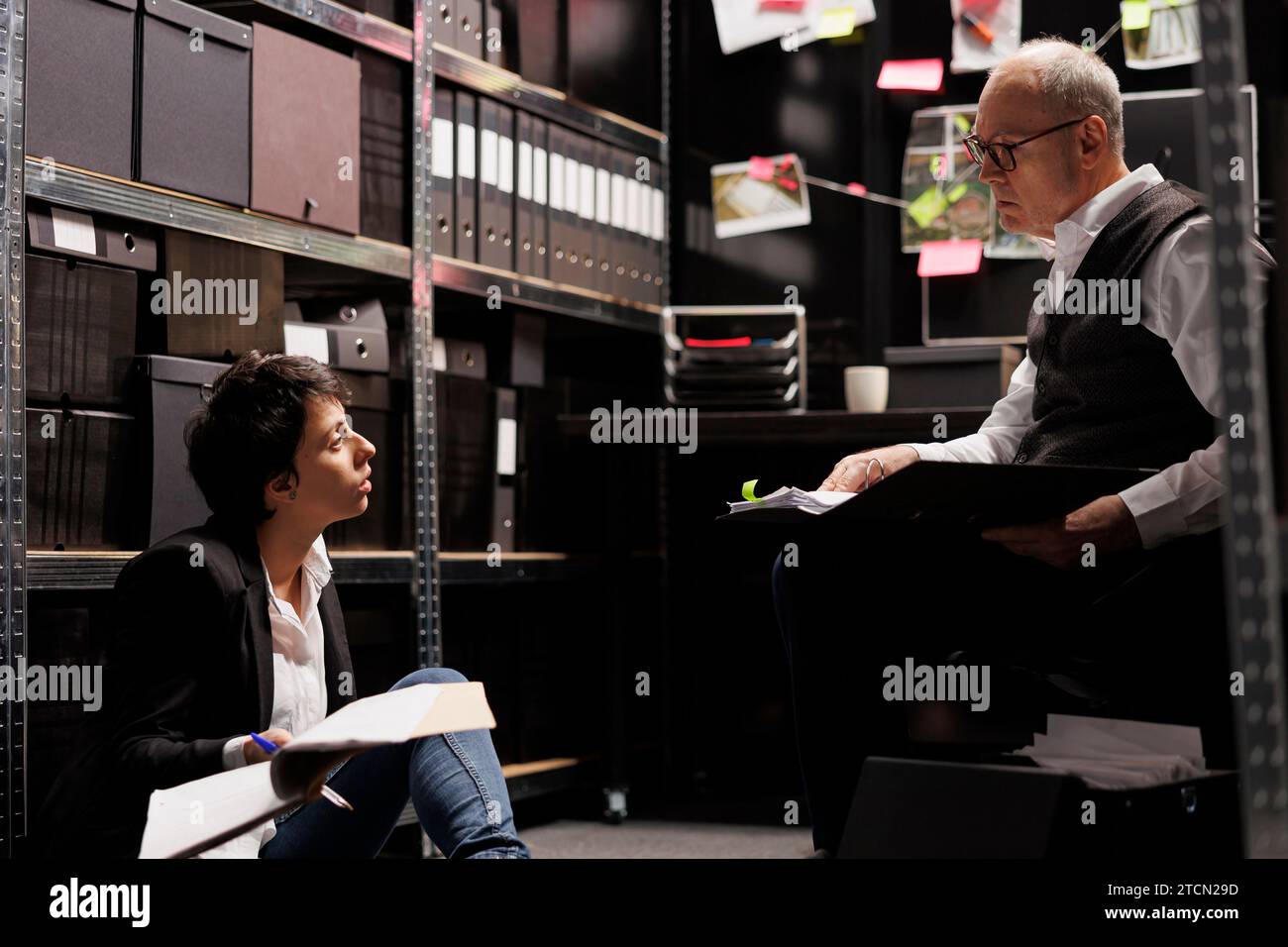 Overworked Police Officers Analyzing Federal Files In Arhive Room Working Late At Night At