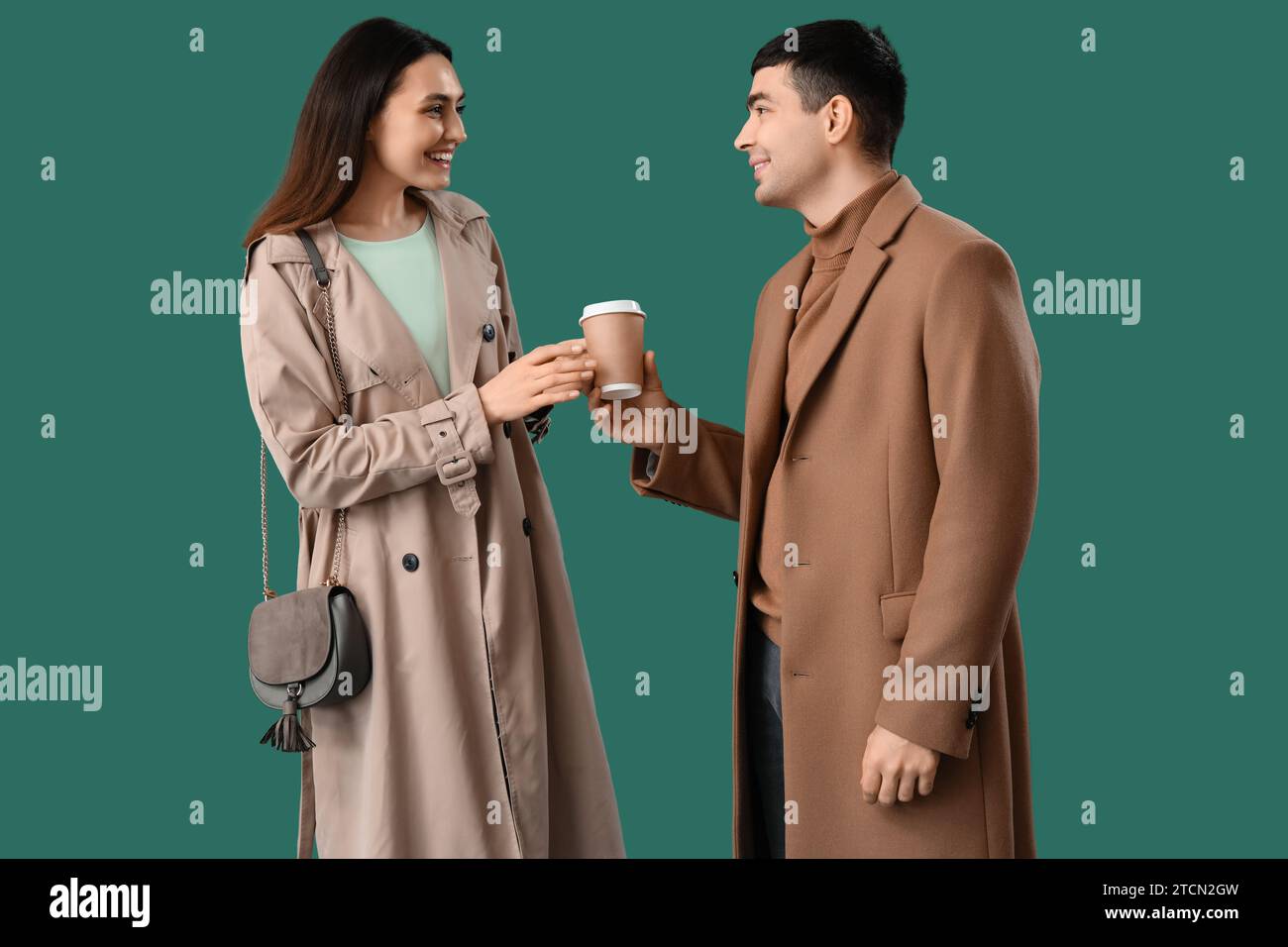 Young man bringing coffee to his girlfriend on green background Stock ...