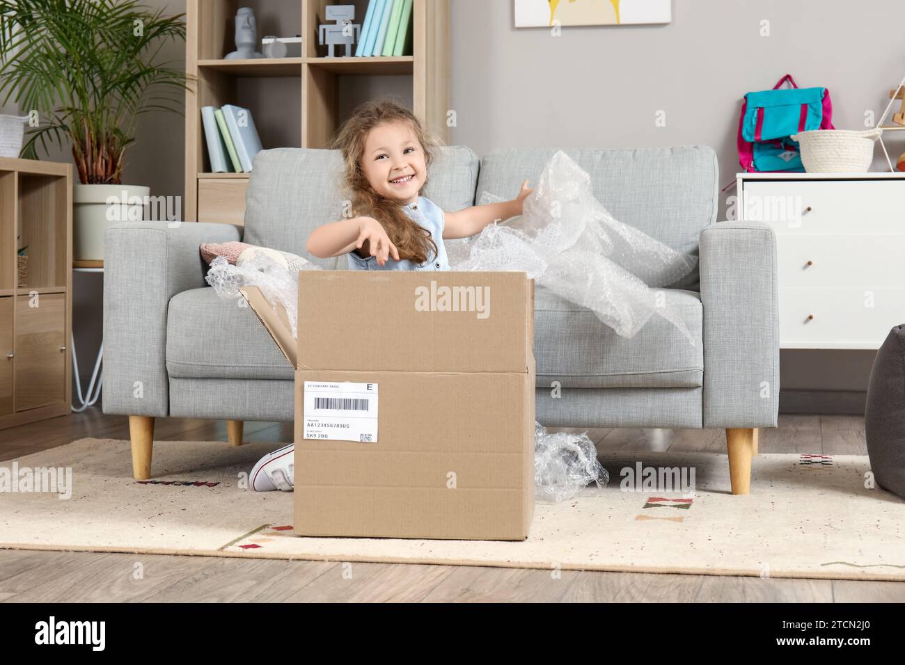 Cute little girl unpacking parcel at home Stock Photo - Alamy