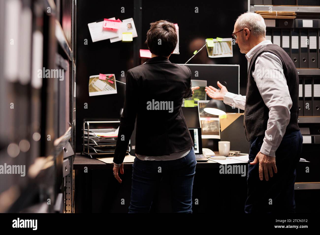 Criminology team looking at investigation board, analyzing crime scene ...