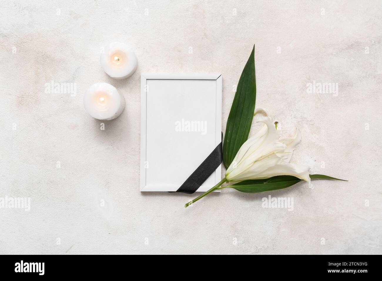 Blank funeral frame, burning candles and lily flower on light ...