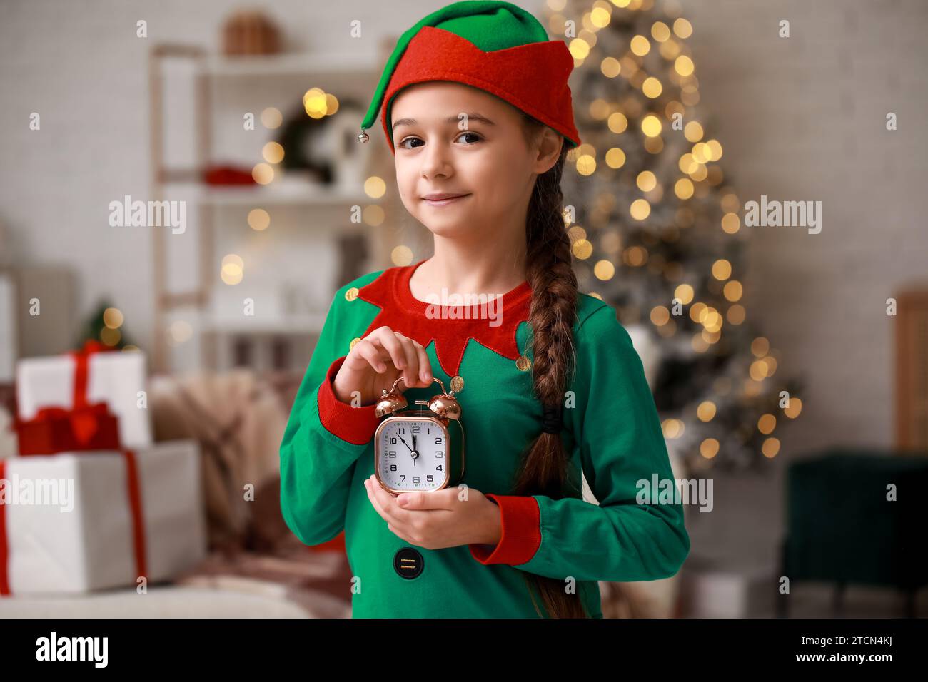 Cute little girl in elf costume with alarm clock at home on Christmas ...
