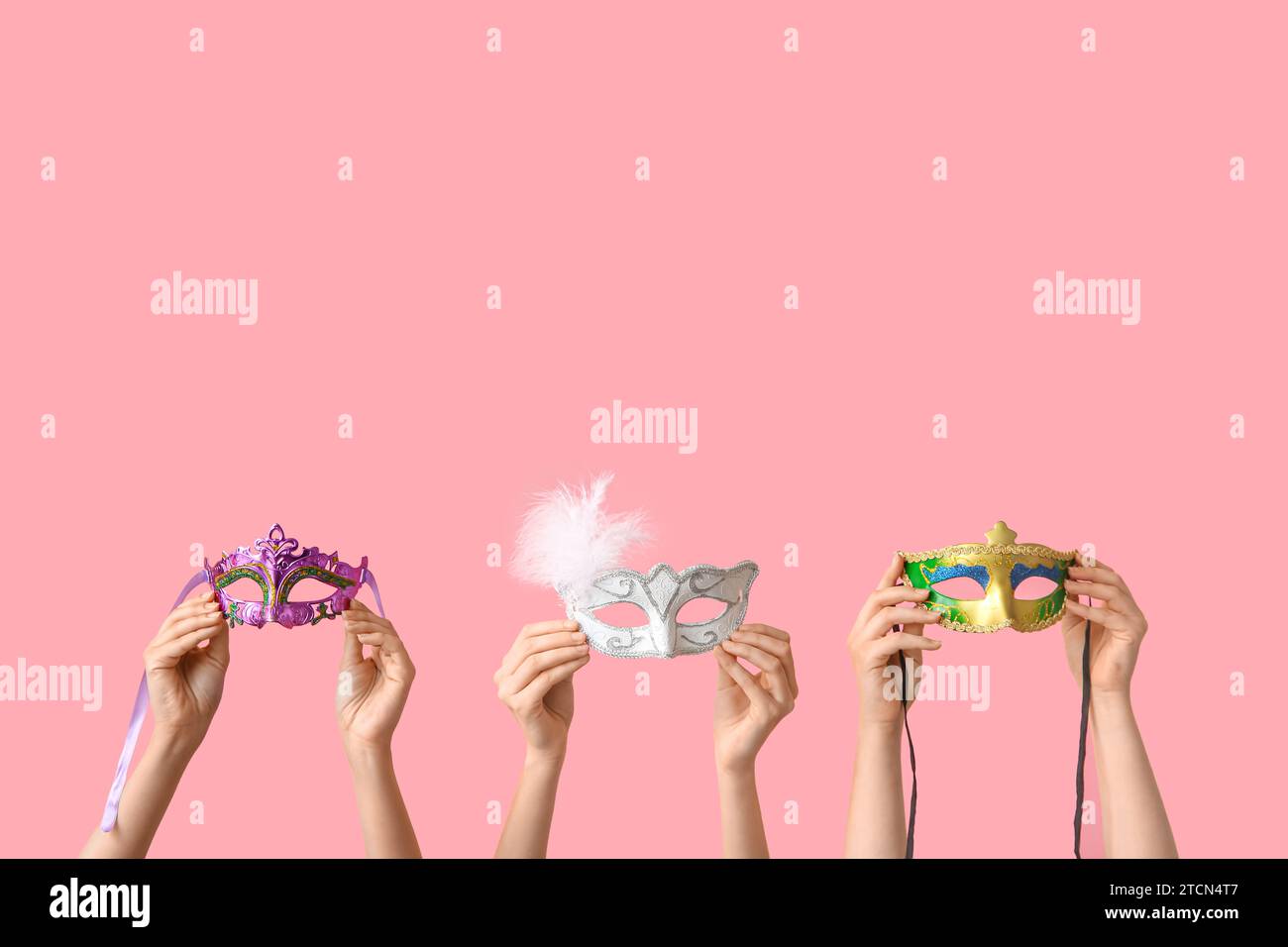 Female hands with carnival masks on pink background Stock Photo - Alamy