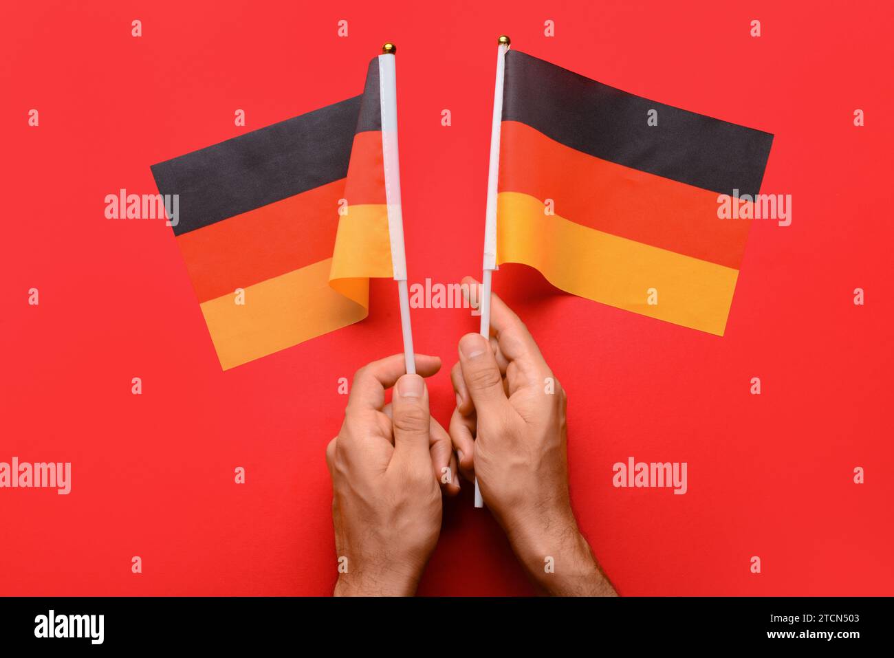 Male hands with flags of Germany on red background Stock Photo - Alamy