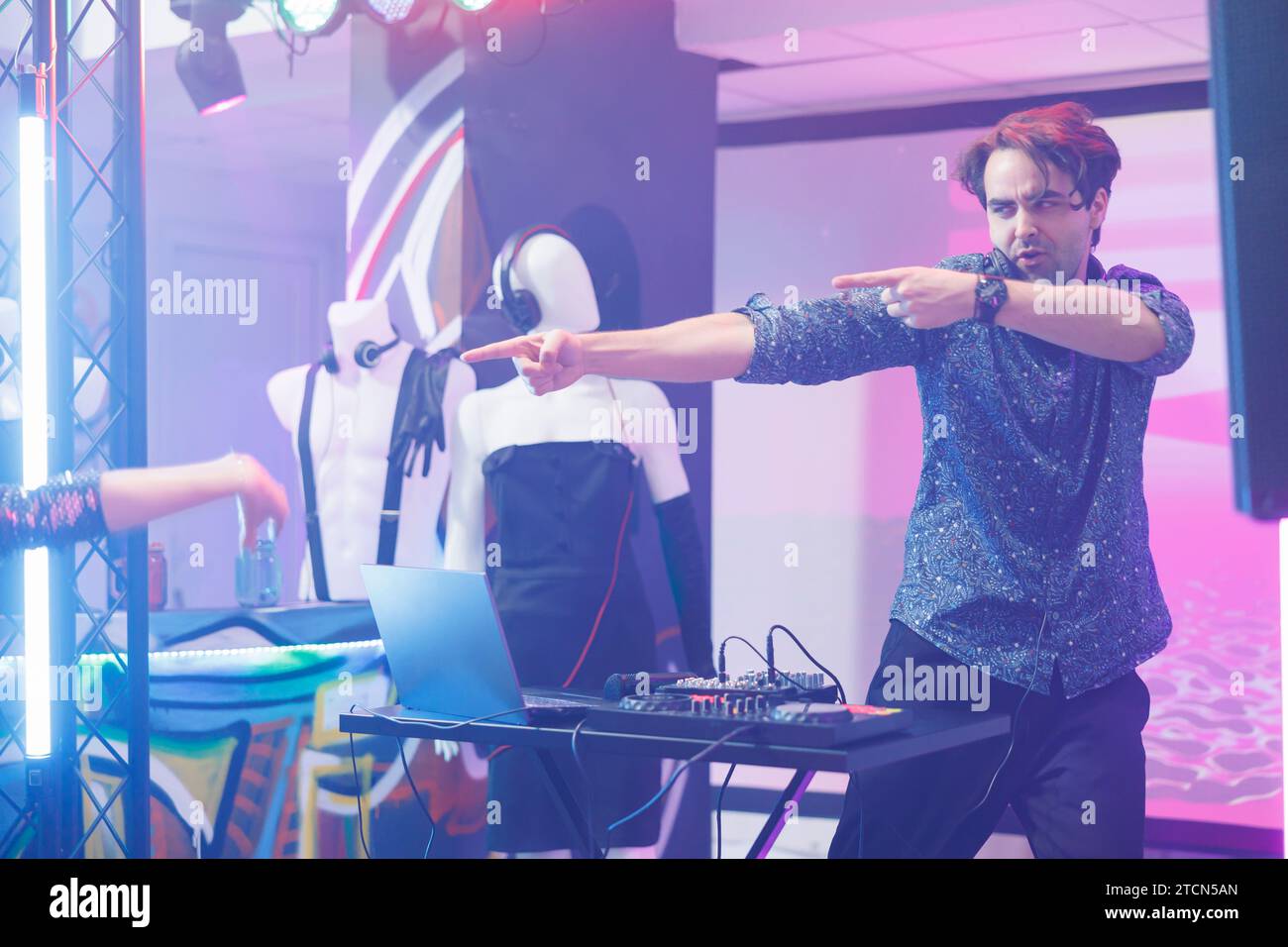 Young dj pointing with fingers at crowd on dancefloor in nightclub ...