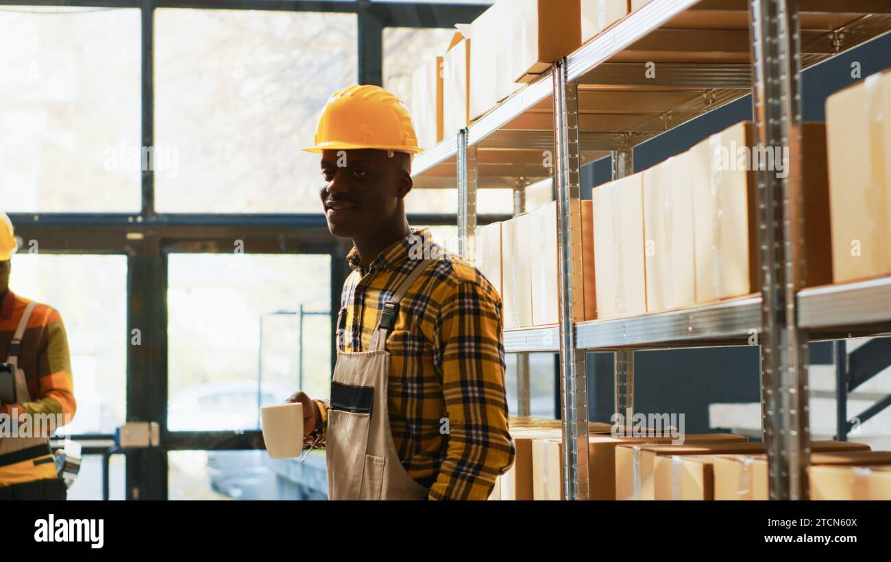 African american warehouse worker posing near shelves filled with ...