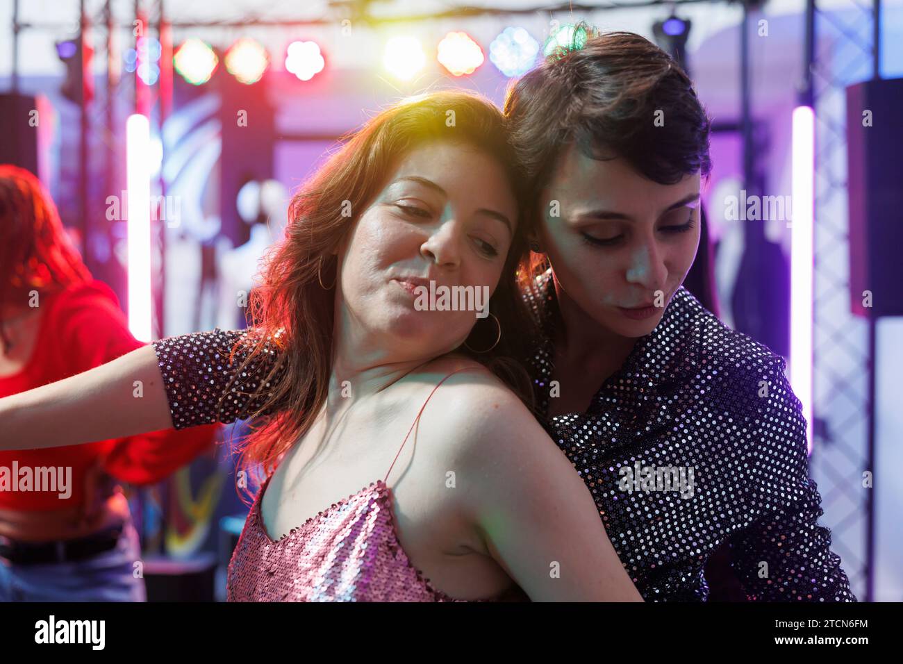 Smiling women hugging while dancing together at nightclub party. Young ...