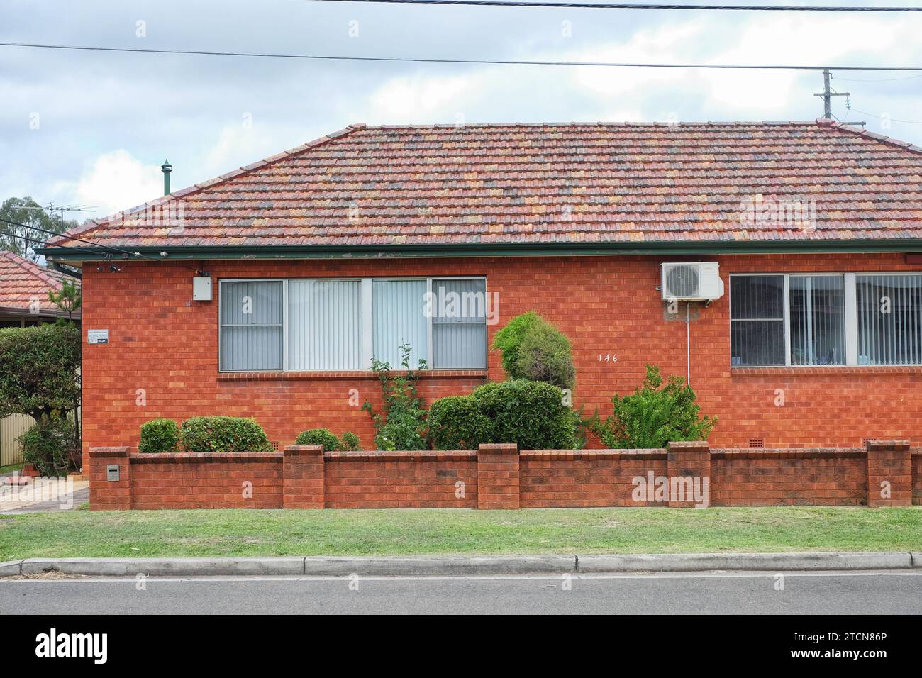 A bare brick single story house with a low brick wall on a suburban ...