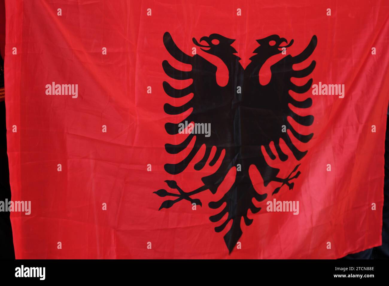 A close-up photo capturing the details of the Albanian flag held in ...