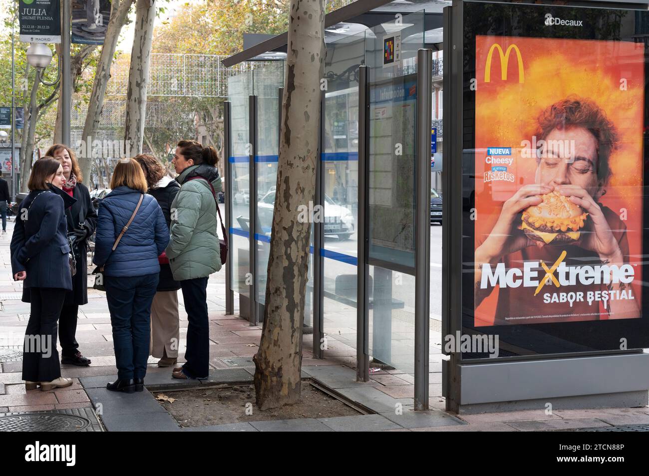 A group of women stands next to a bus stop as a McDonald's commercial ...