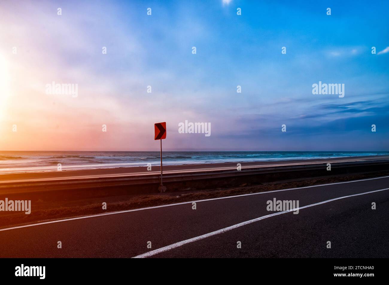 The road turns along the beach at sunset Stock Photo - Alamy