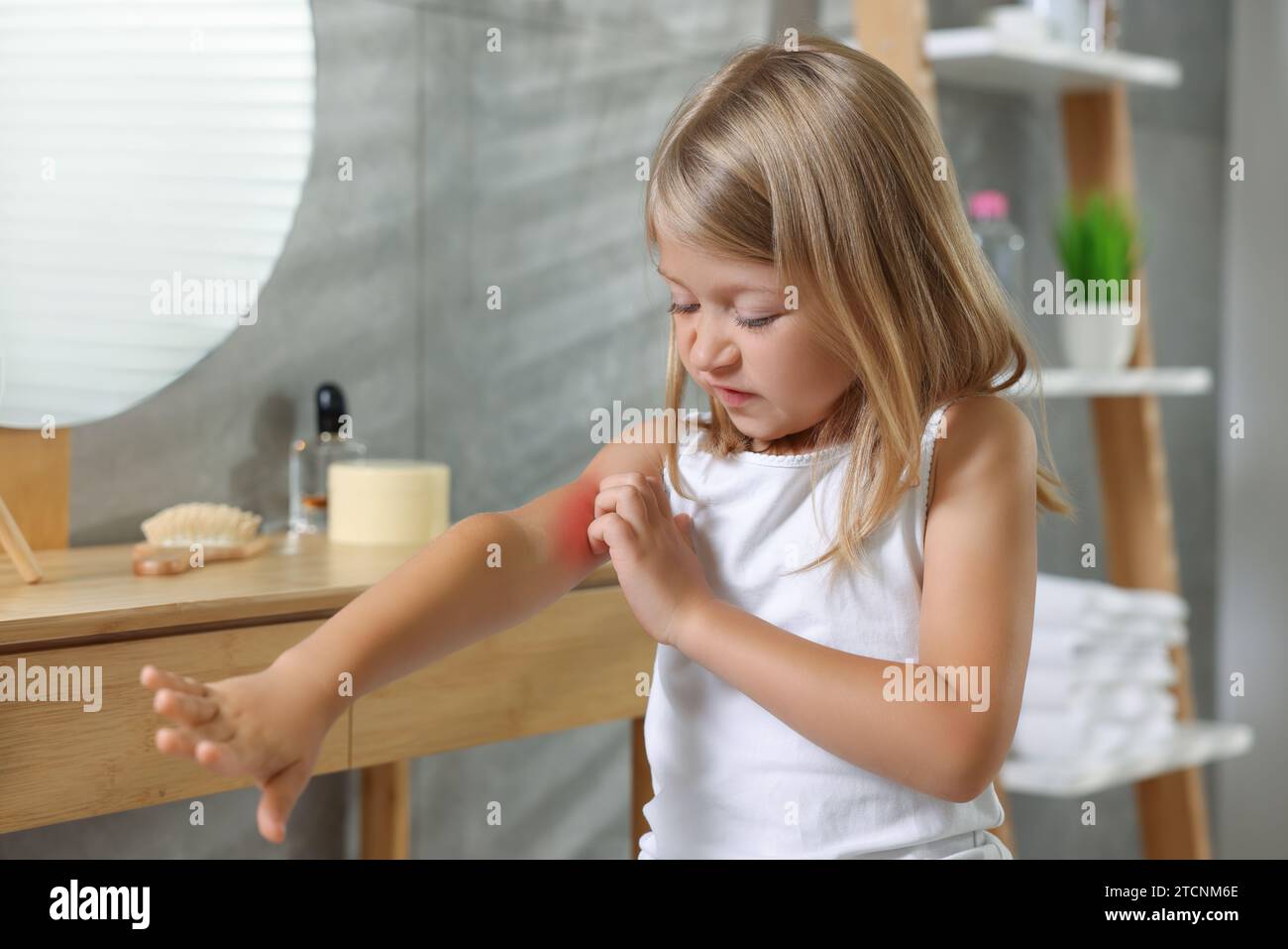Suffering from allergy. Little girl scratching her arm in bathroom ...