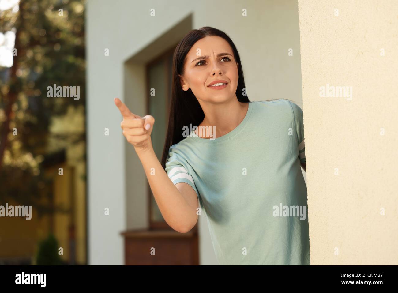 Angry young woman pointing near house. Annoying neighbour Stock Photo ...