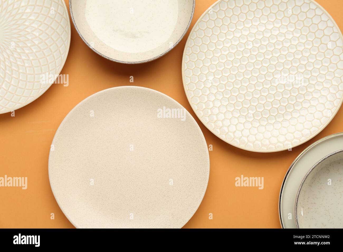 Beautiful beige ceramic plates on orange background, flat lay Stock ...