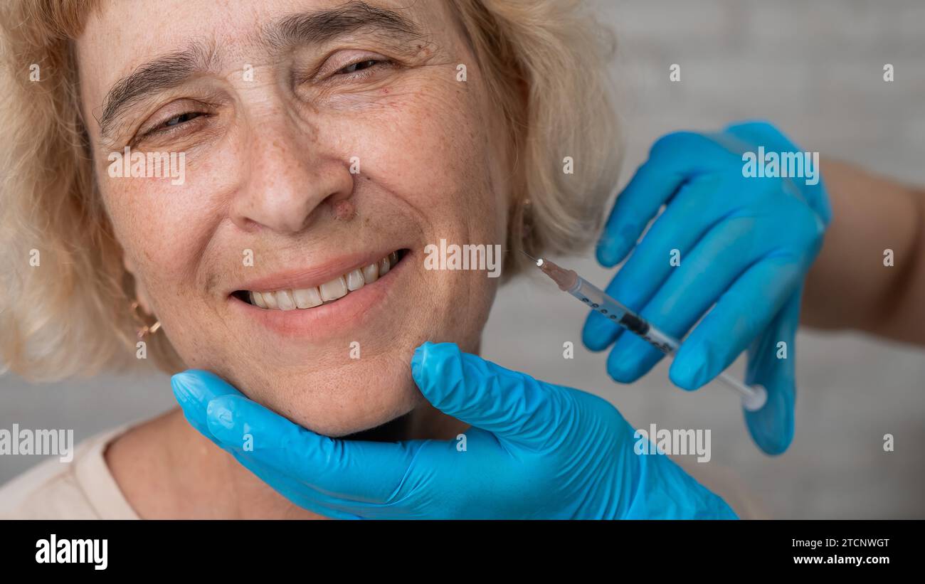 Doctor makes beauty injections in the face of an old caucasian woman ...