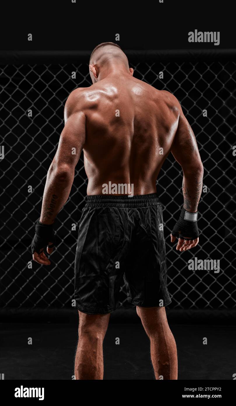 Conceptual image of a kickboxer. A real fighter stands in the real cage ...