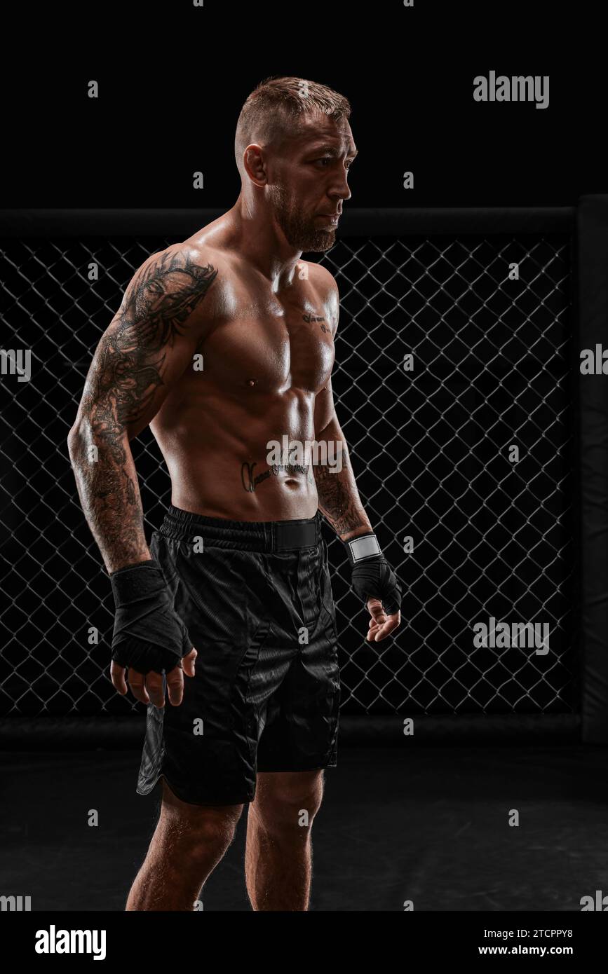 Conceptual image of a kickboxer. A real fighter stands in the real cage ...