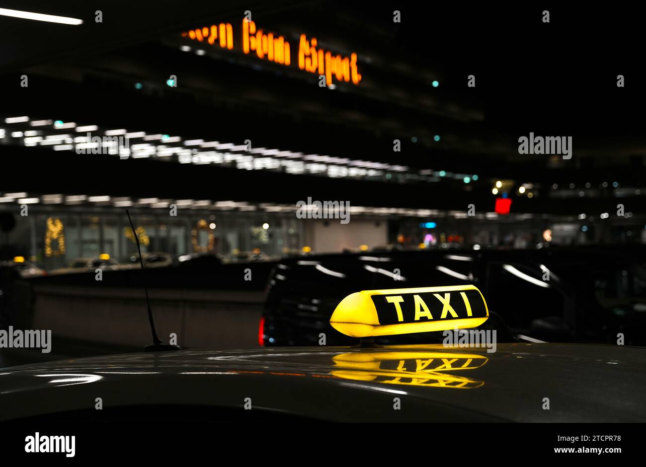 An illuminated taxi sign of a waiting cab at the airport at night with ...