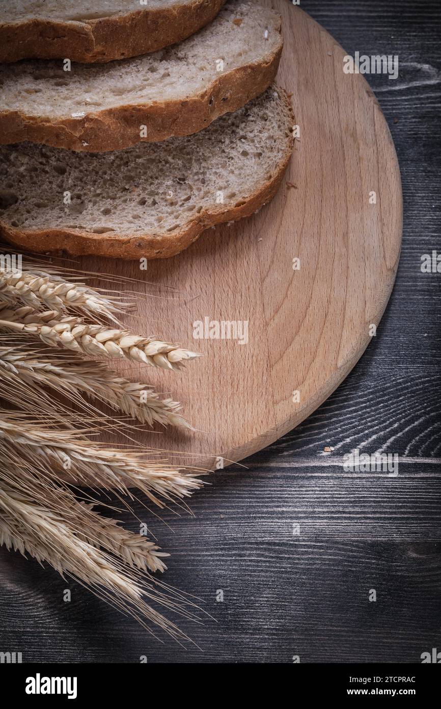 Sliced bread on wooden cutting board Bundle of wheat rye ears vertical ...