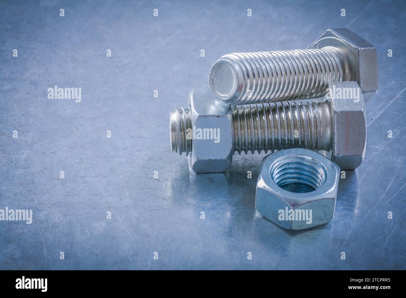 Horizontal view of stainless screws and nuts on a metallic background ...