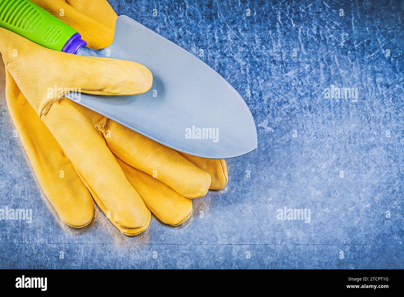 Yellow safety gloves metal hand spade on metallic background gardening ...