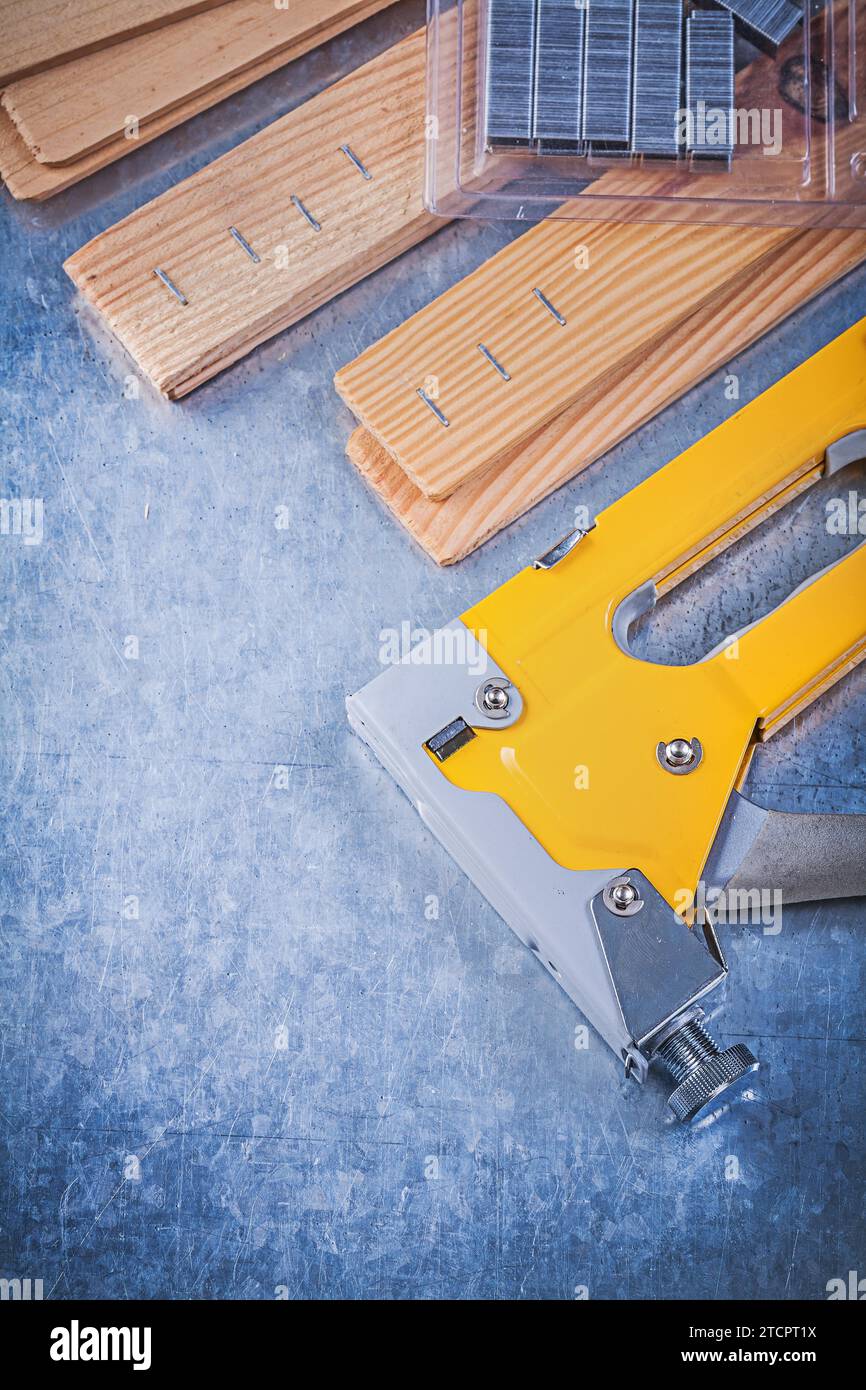 Yellow staple gun metal staples wooden boards on metallic background ...