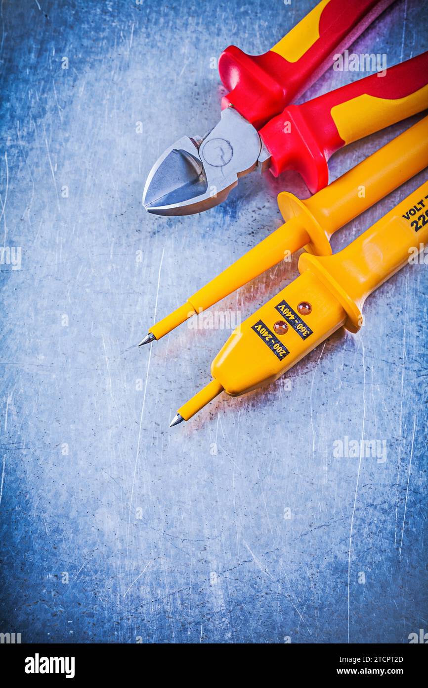 Yellow electrical tester Red sharp wire cutter on metallic background ...