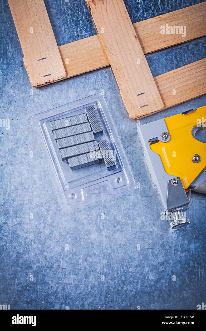 Assortment of stapler gun metal staples wooden board on metallic ...