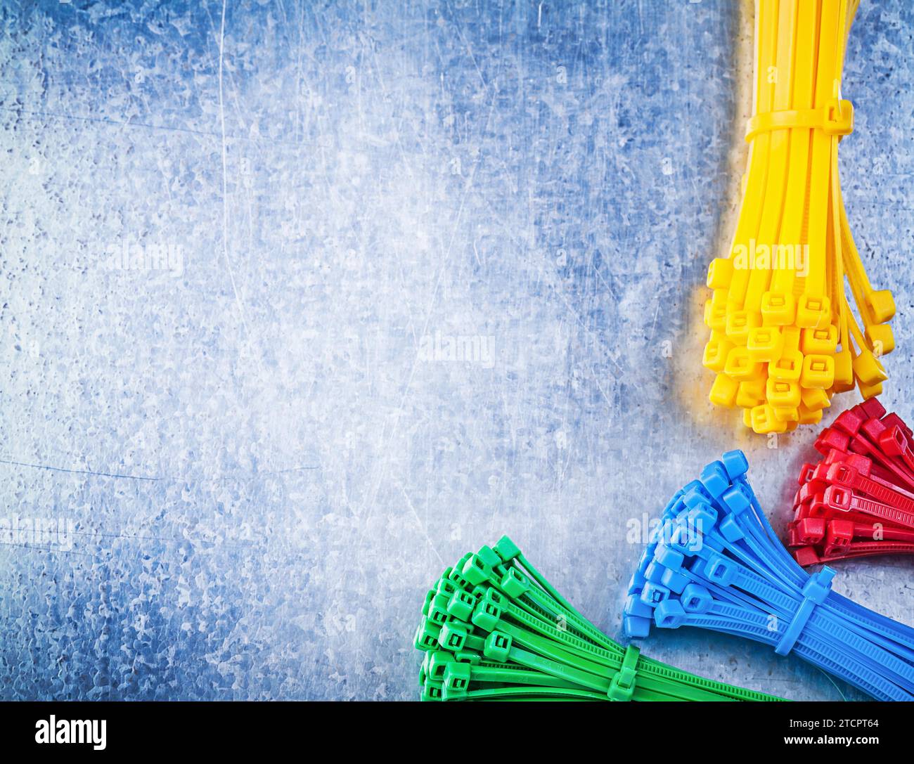 Assortment of multicoloured plastic cable ties on scratched metallic ...