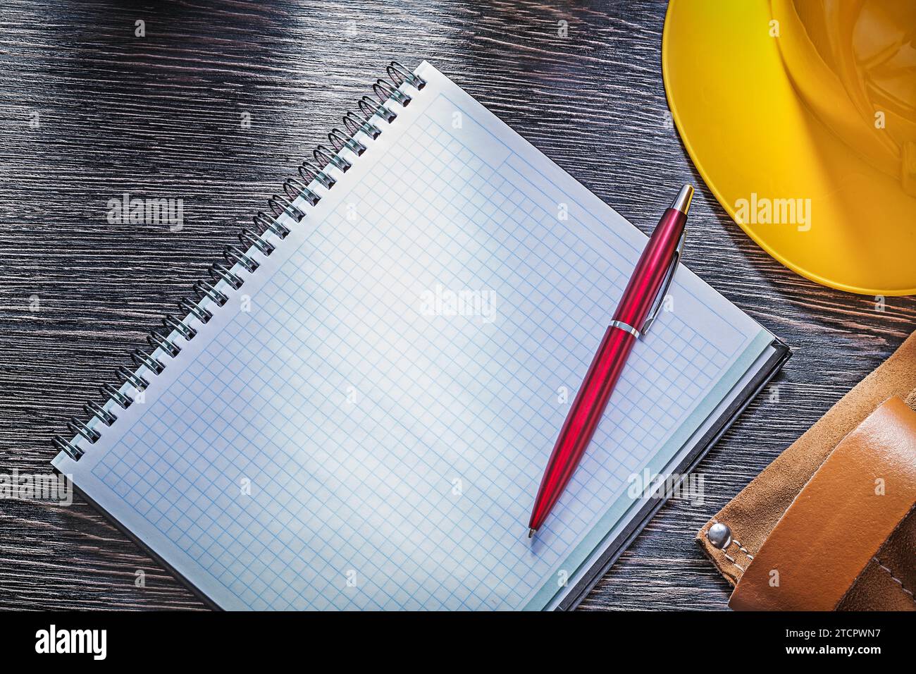 Leather tool belt, construction helmet, chequered notepad, pen on ...