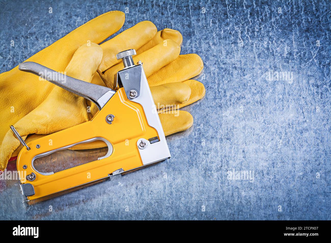 Pair of leather safety gloves stapler gun on metallic background ...