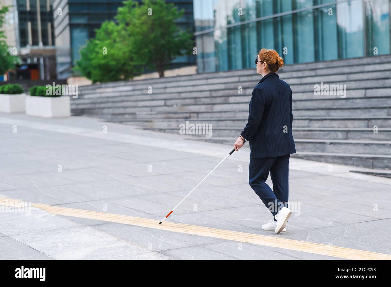 Blind businesswoman walking along tactile tiles with a cane Stock Photo ...