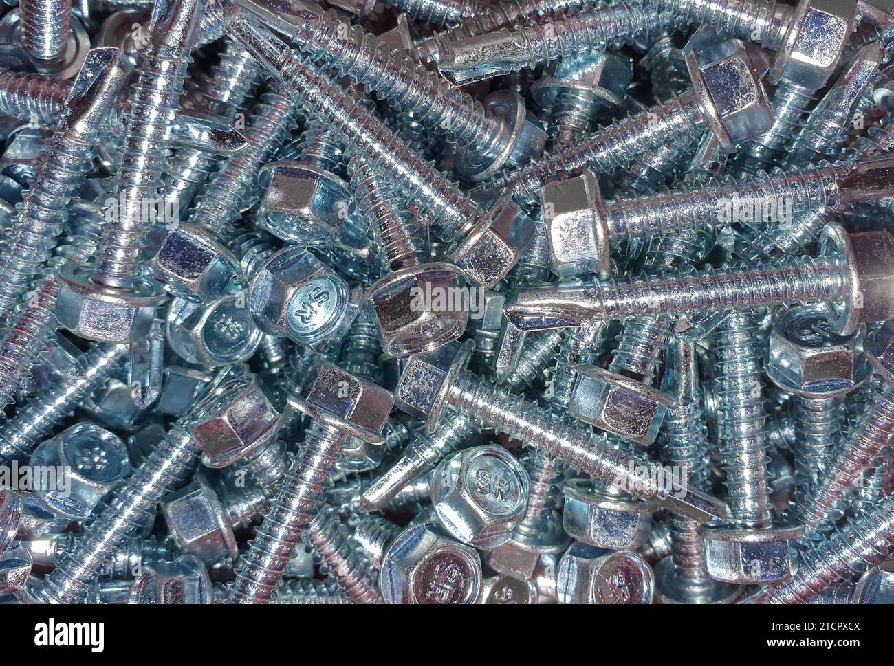 A macro shot of an assortment of screws and nuts scattered on a solid ...