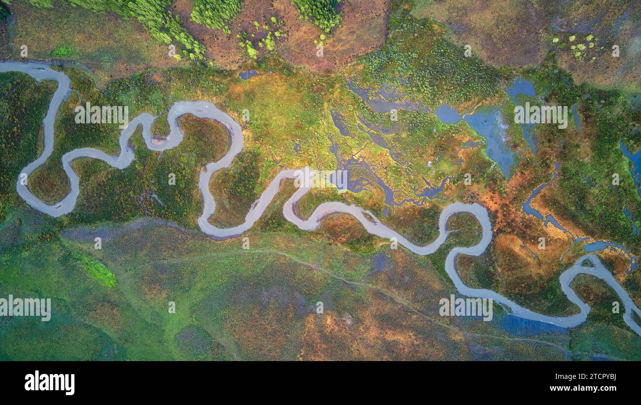 Aerial photograph of a winding river cutting through lush green land, surrounded by trees and ...