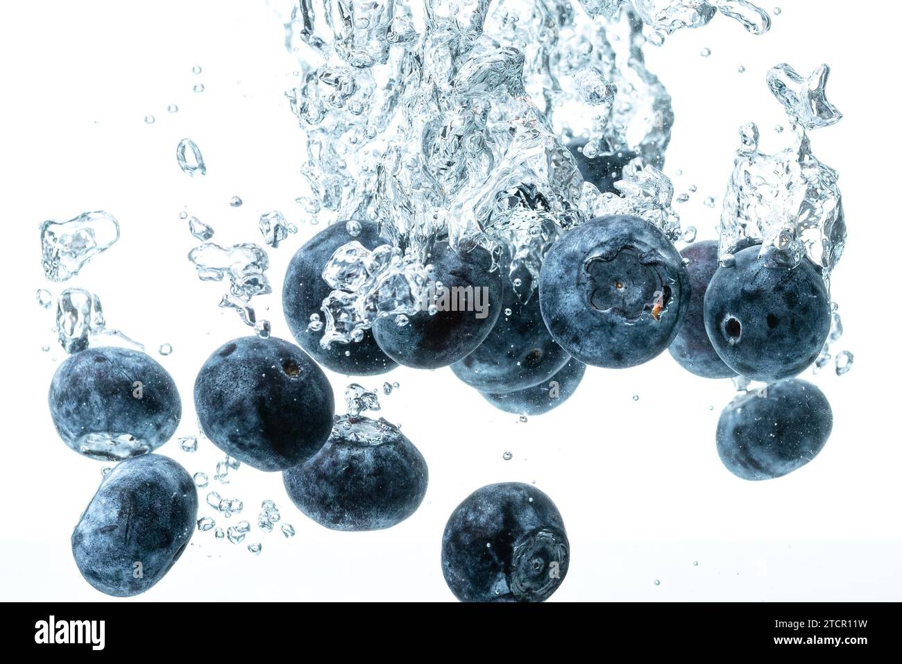 Blueberries sinking into water with air bubbles white background ...
