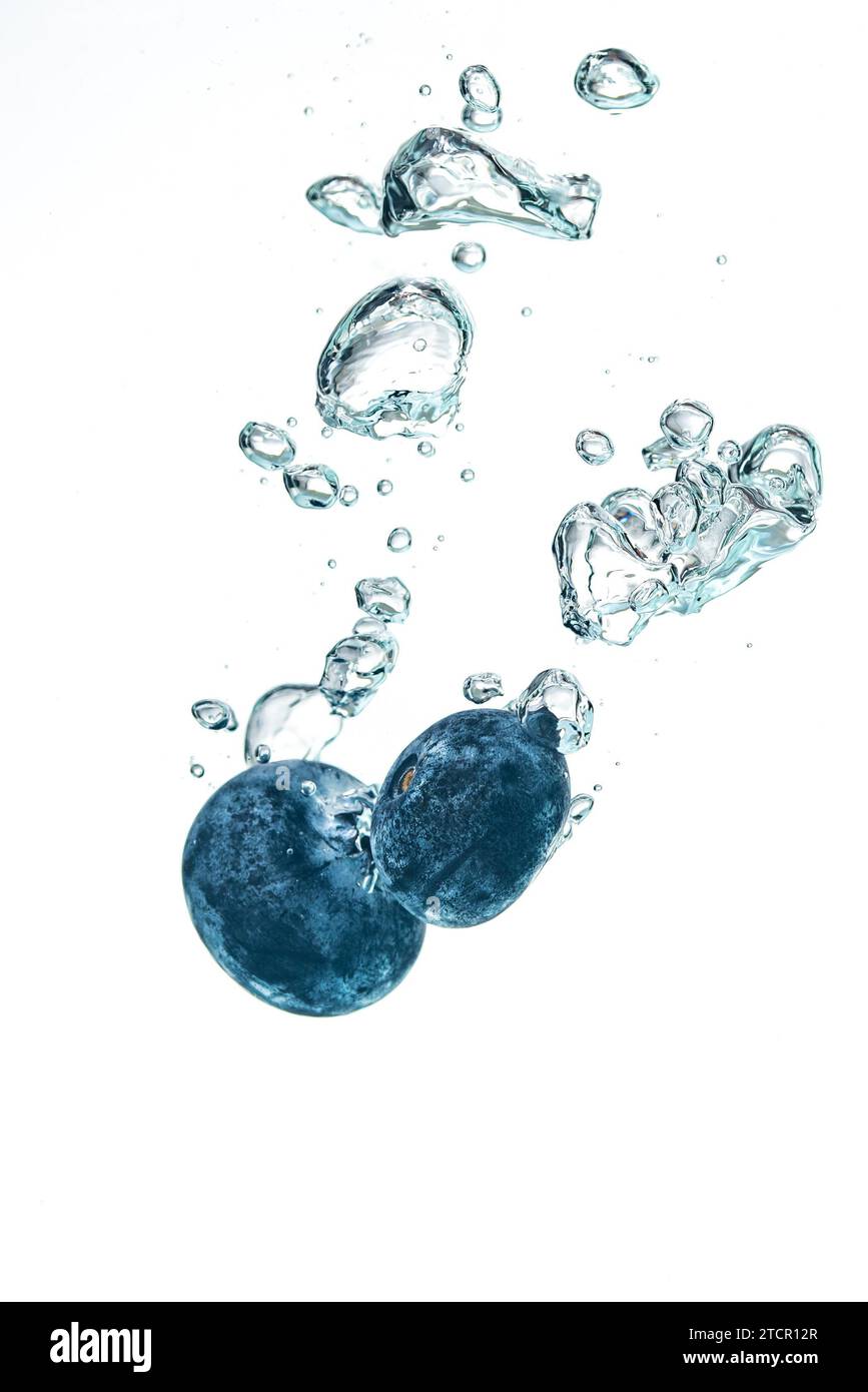 Two blueberry?s splashing into crystal clear water with air bubbles ...